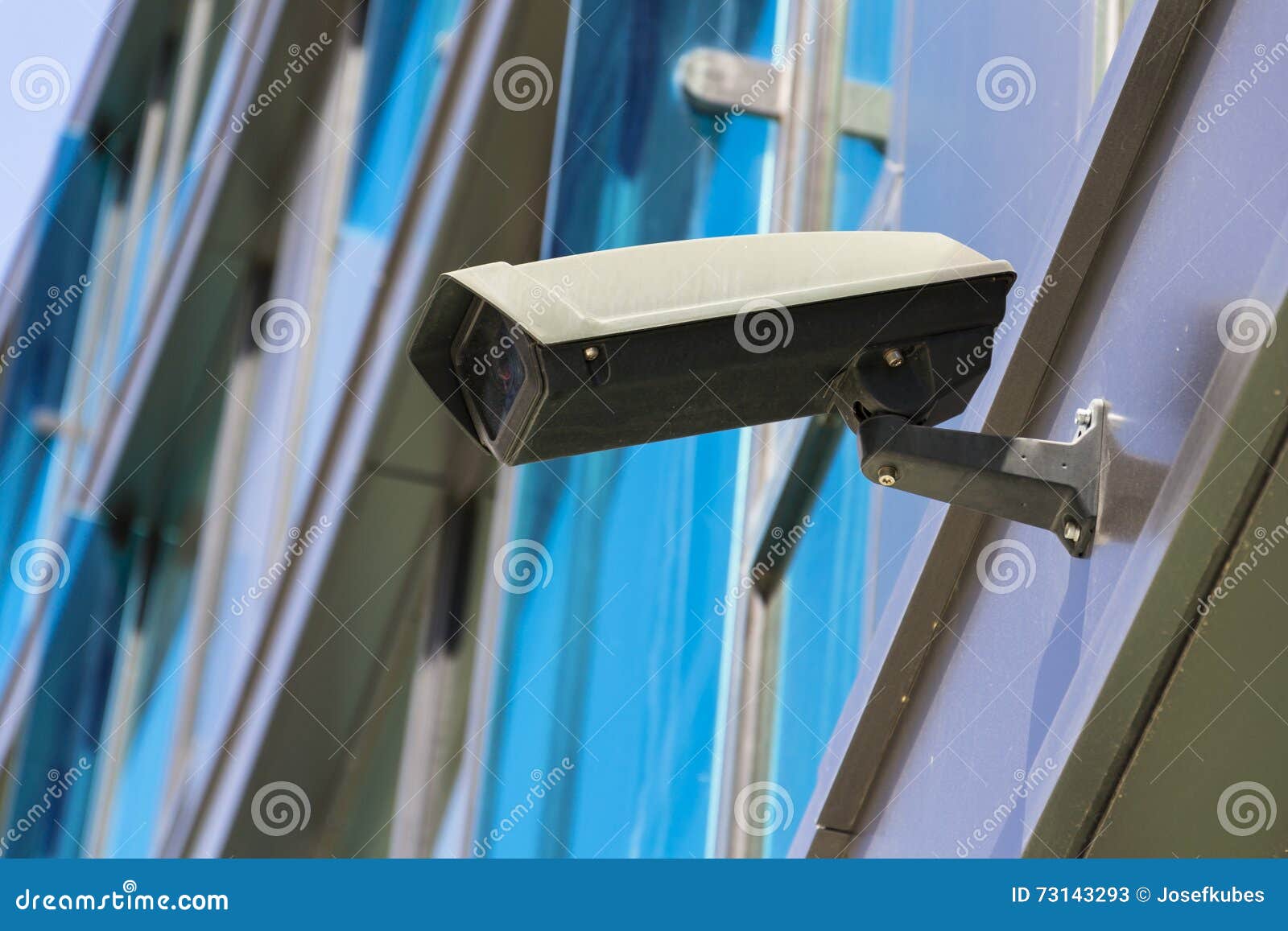 Grey Security Camera Attached To Wall with Blue Windows in Background ...
