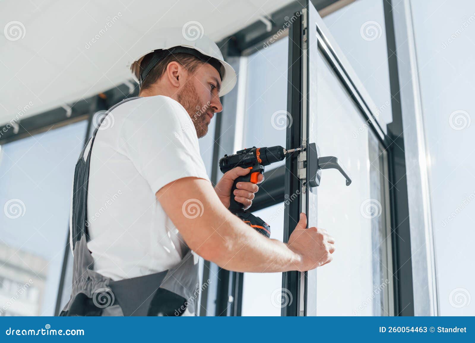 In Grey Uniform. Repairman is Working Indoors in the Modern Room Stock ...