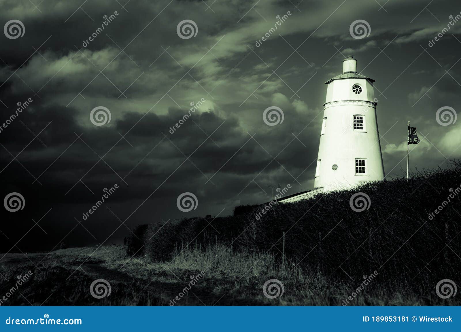 Greyscale Shot of a Magnificent Lighthouse on the Grass-covered Hill ...
