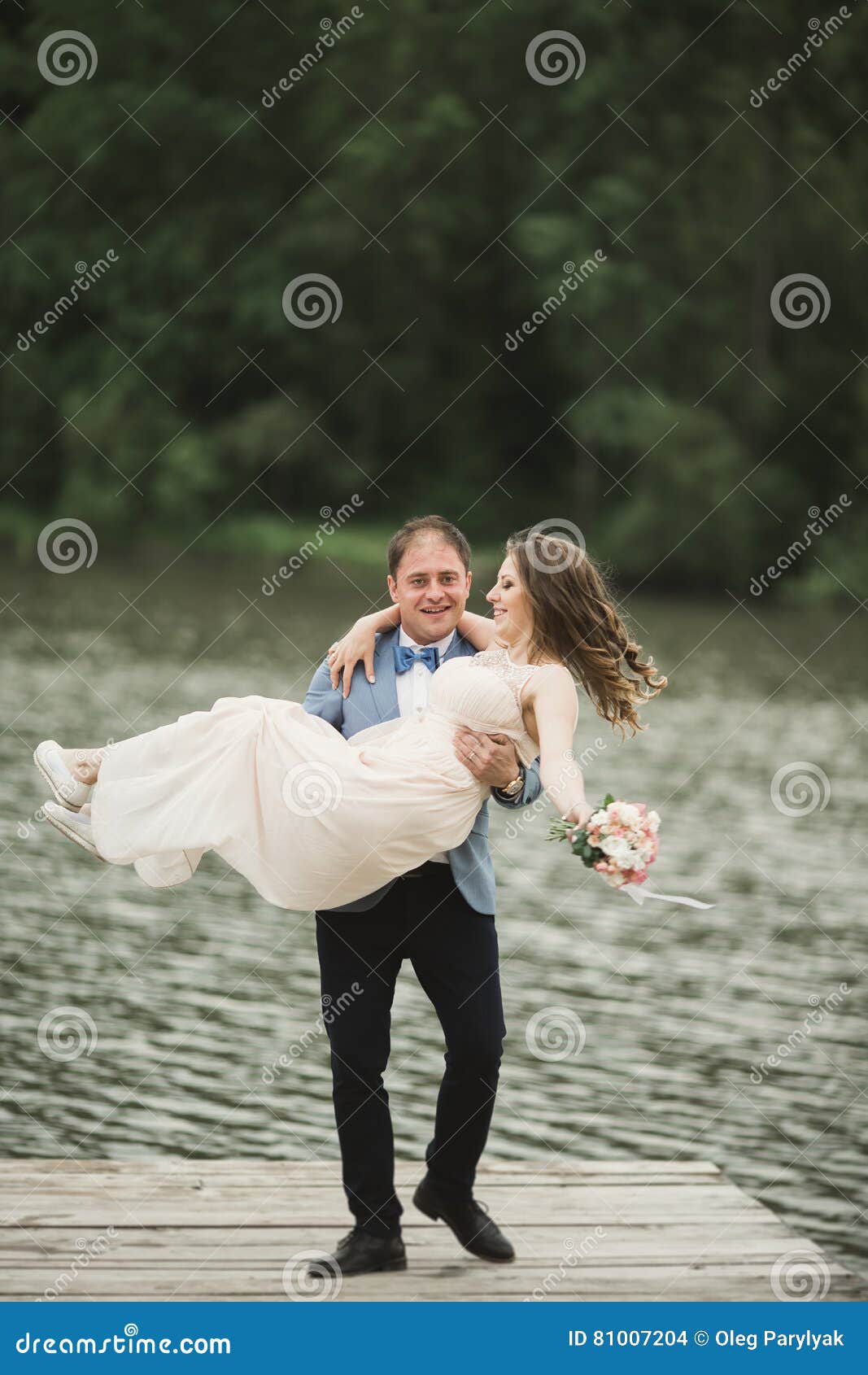 Groom Carrying Bride Near Lake and Forest Stock Photo - Image of ...