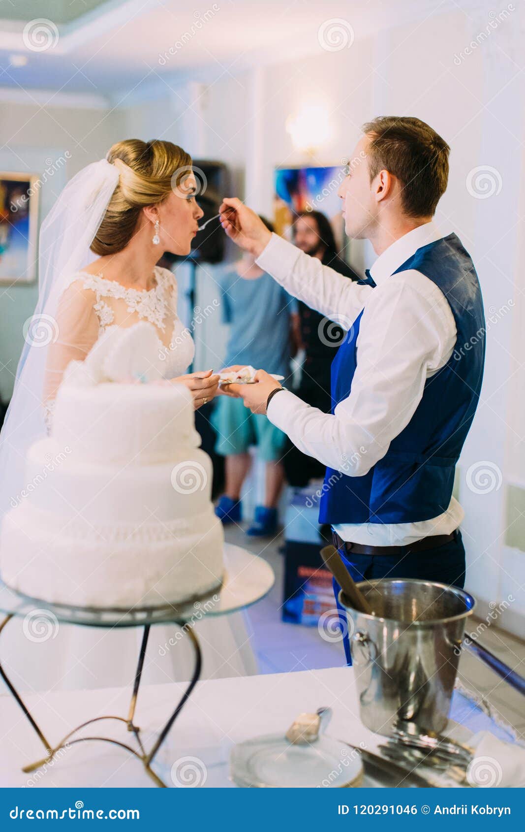 The Groom is Feeding the Bride with the Wedding Cake. Stock Photo ...