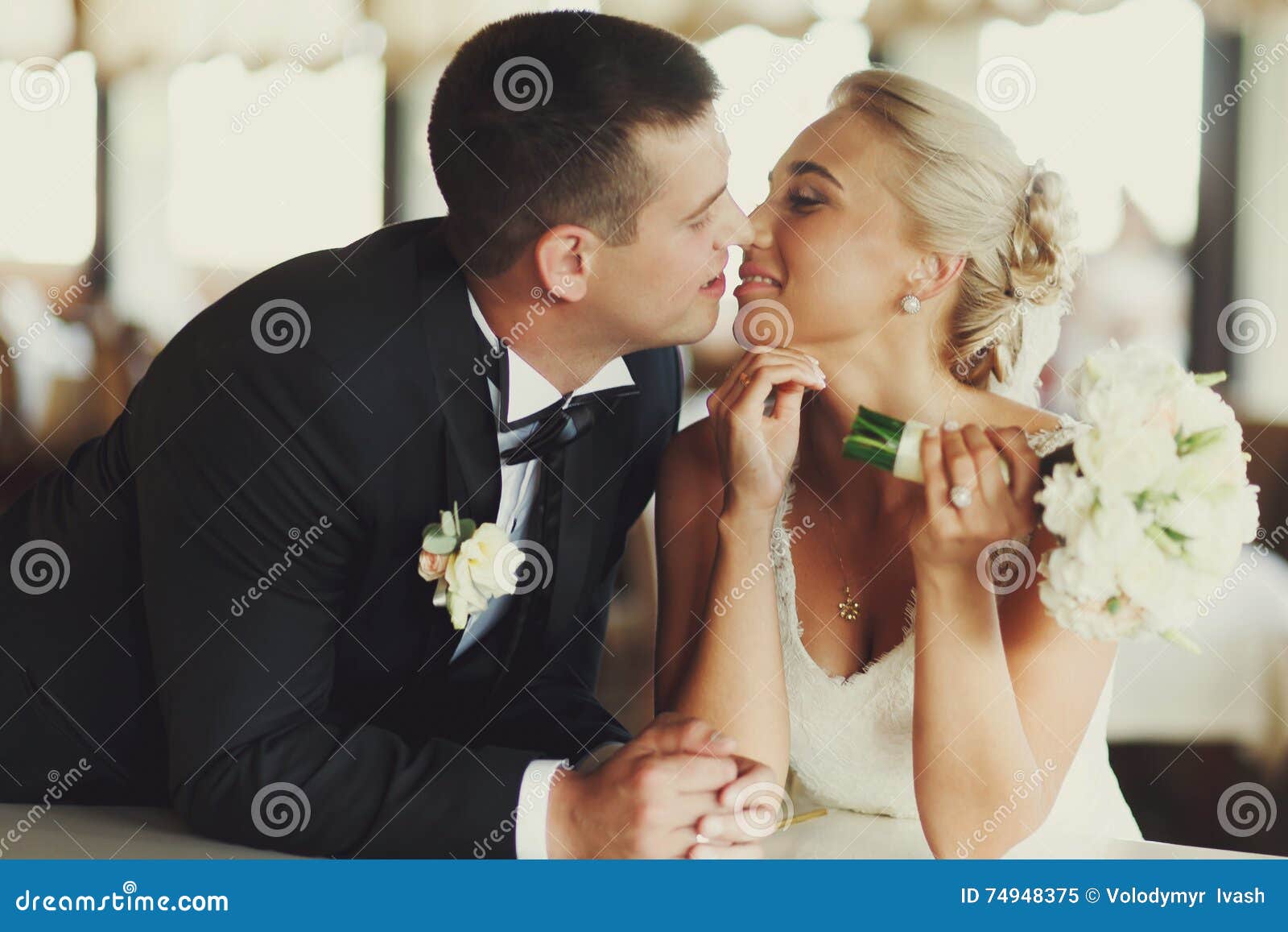 Groom Kisses a Bride Leaning on the Table Stock Image - Image of hall ...