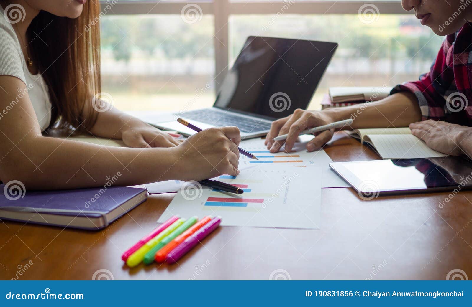 A Group of Asian Students Sit and Do Homework and Report in the Library ...
