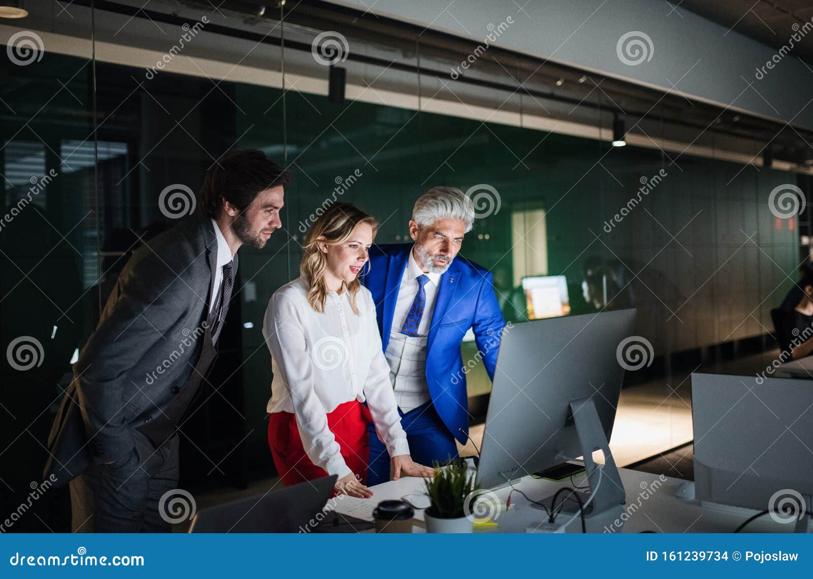 A Group of Businesspeople in an Office at Night, Using Computer. Stock ...