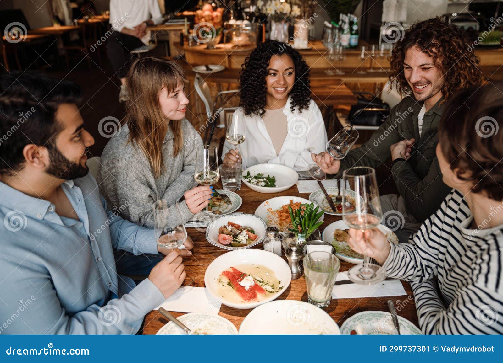 Group of Cheerful Friends Talking and Drinking Wine while Dining in ...