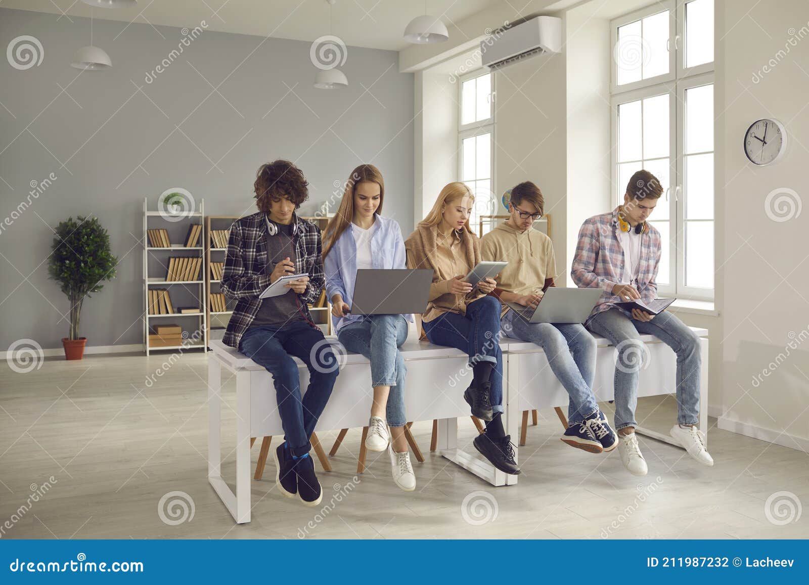 College Students Sitting in Classroom, Using Devices, Reading Notes and ...