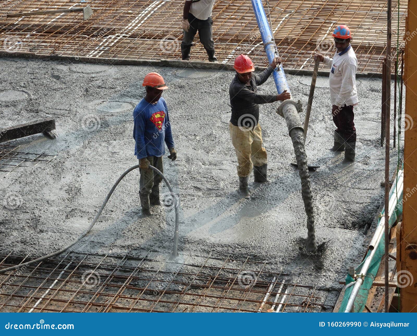Group Of Construction Workers Pouring Wet Concrete Using The Concrete