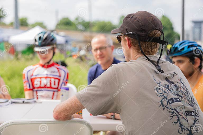 Group of Cyclists in Conversation at an Outdoor Event with Helmets and ...