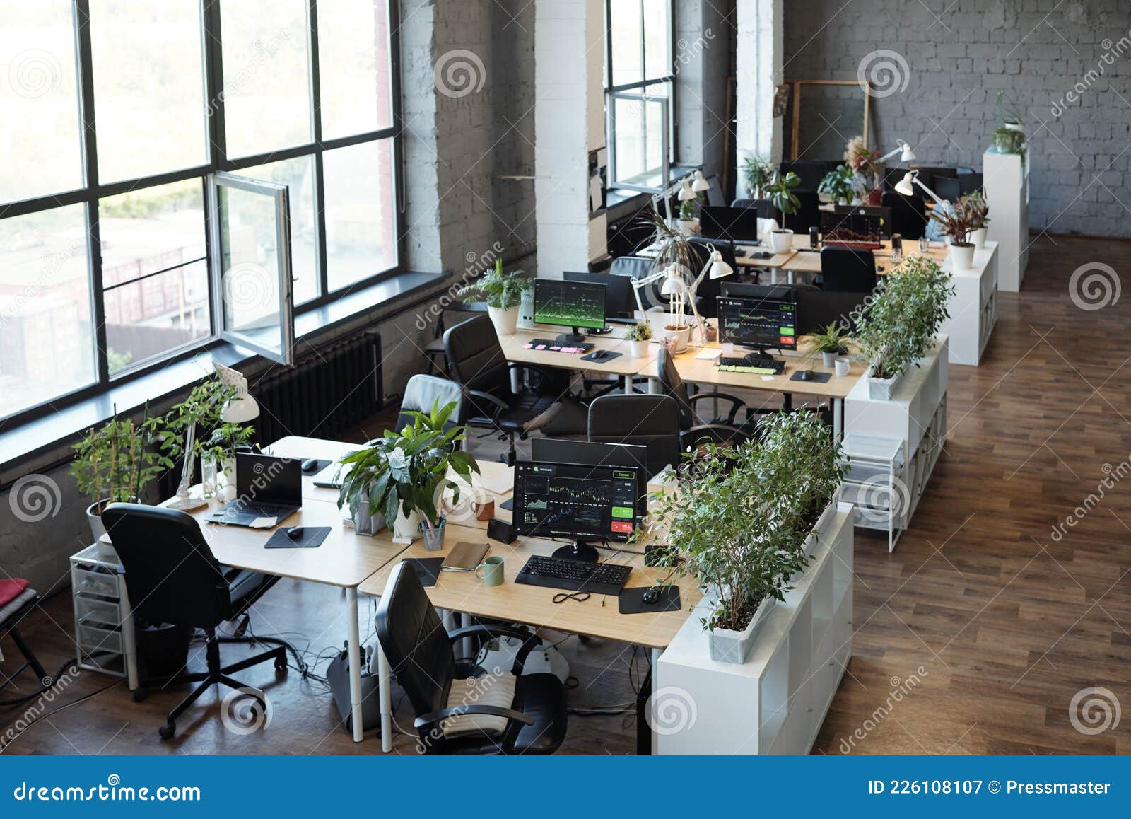Group of Desks with Computer Monitors Standing Along Large Windows ...