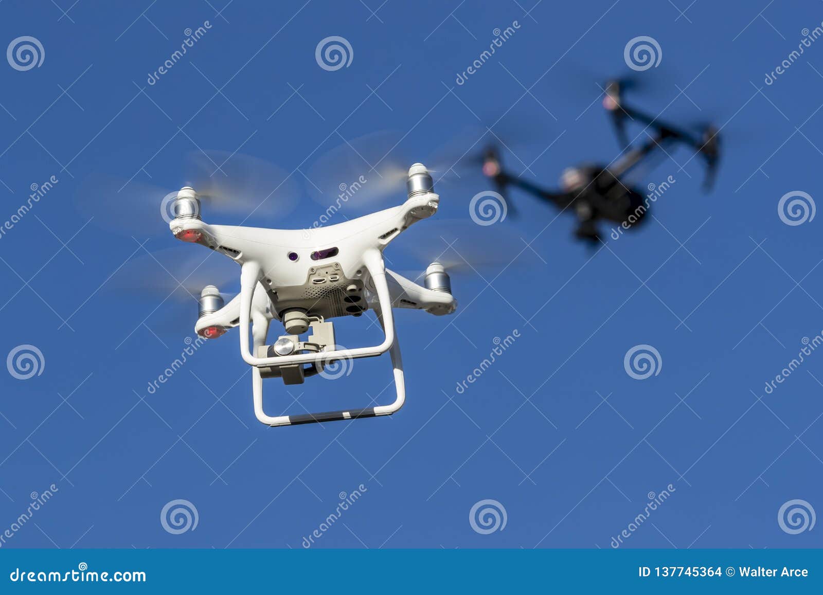 A Group of Drones Fly Together through the Air Against a Blue Sky Stock ...
