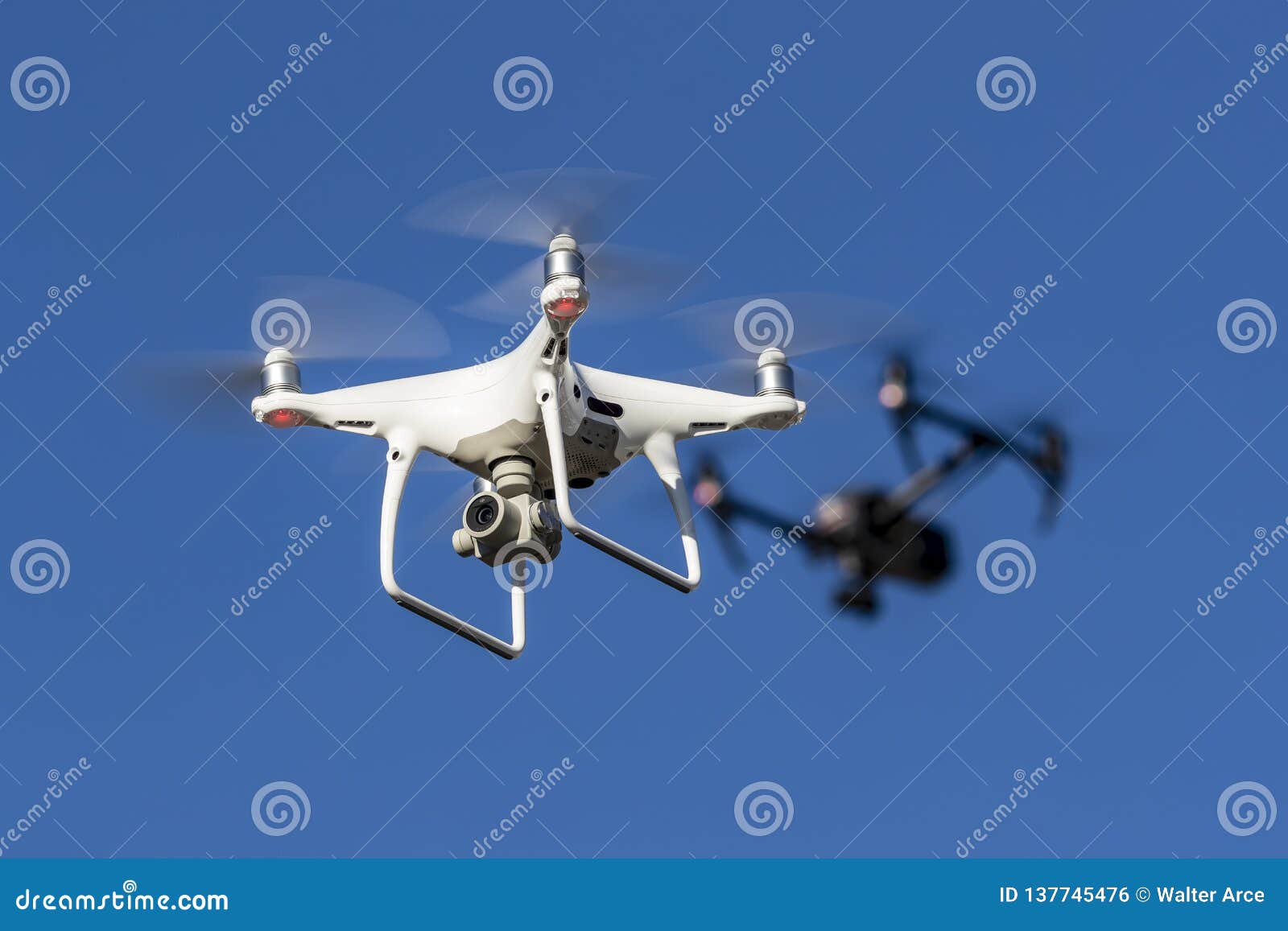 A Group of Drones Fly Together through the Air Against a Blue Sky Stock ...