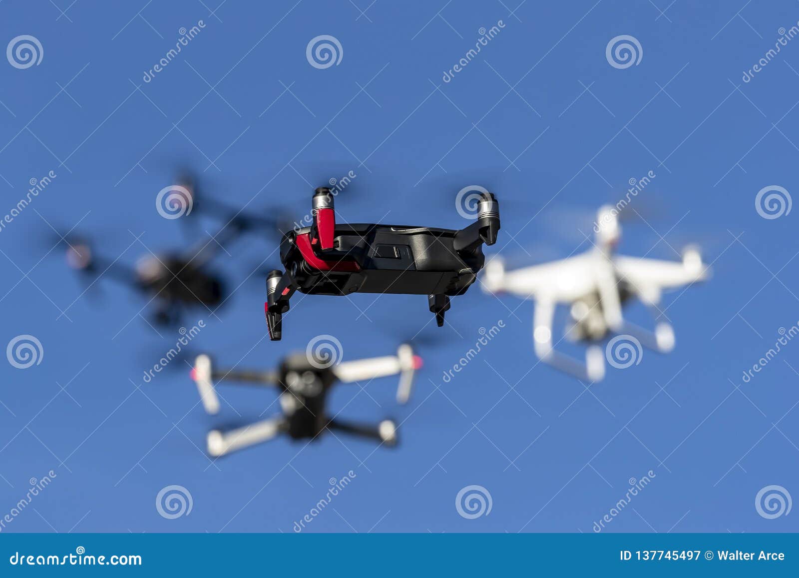 A Group of Drones Fly Together through the Air Against a Blue Sky Stock ...