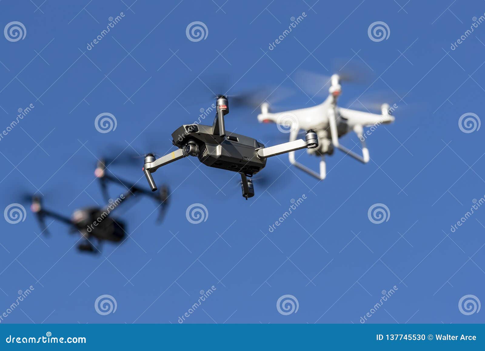 A Group of Drones Fly Together through the Air Against a Blue Sky Stock ...
