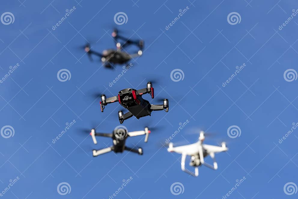 A Group of Multiple Drones Fly Together through the Air Against a Blue ...