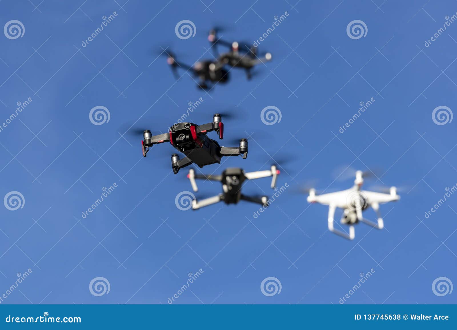 A Group of Multiple Drones Fly Together through the Air Against a Blue ...
