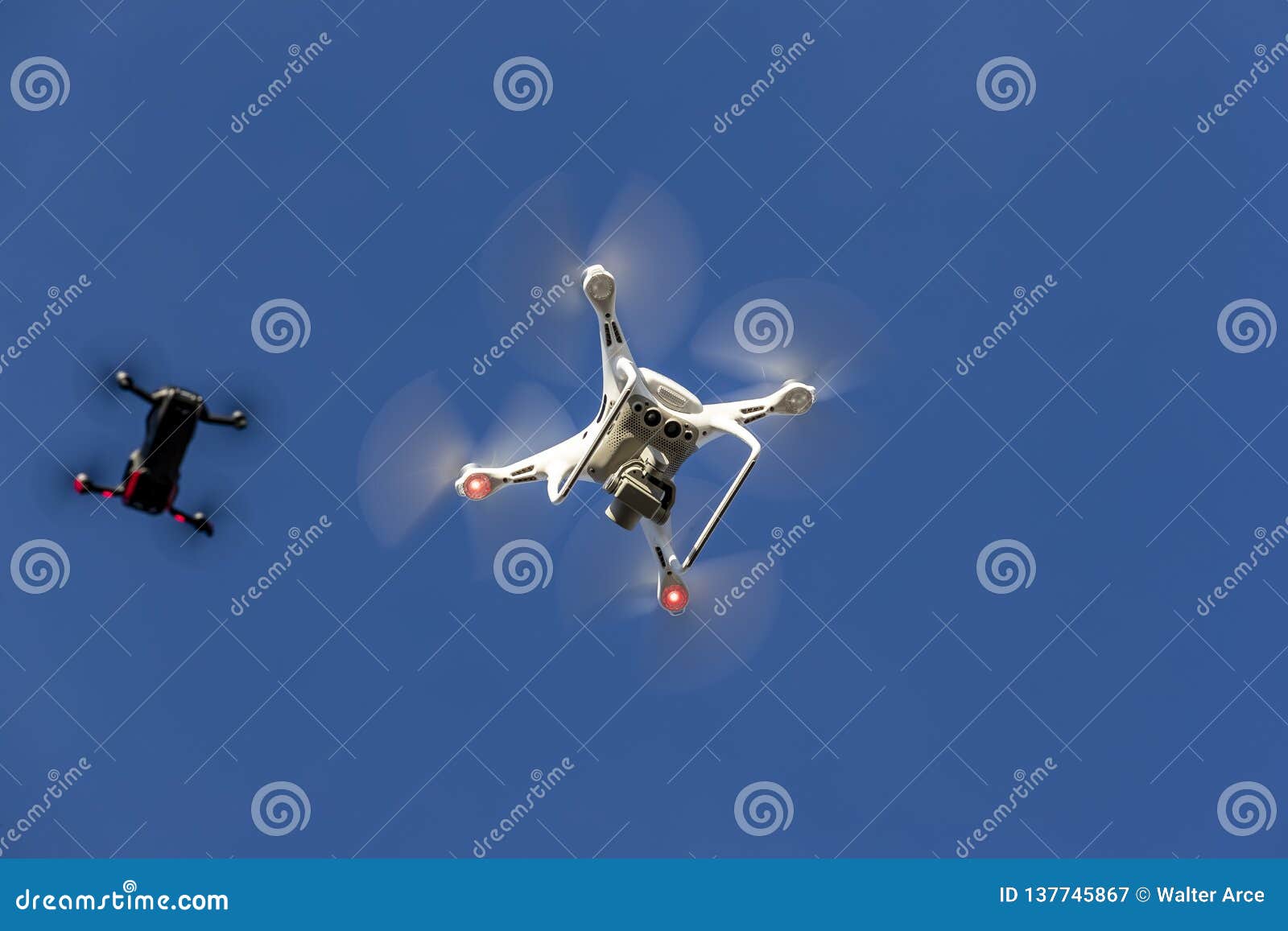 A Group of Multiple Drones Fly Together through the Air Against a Blue ...