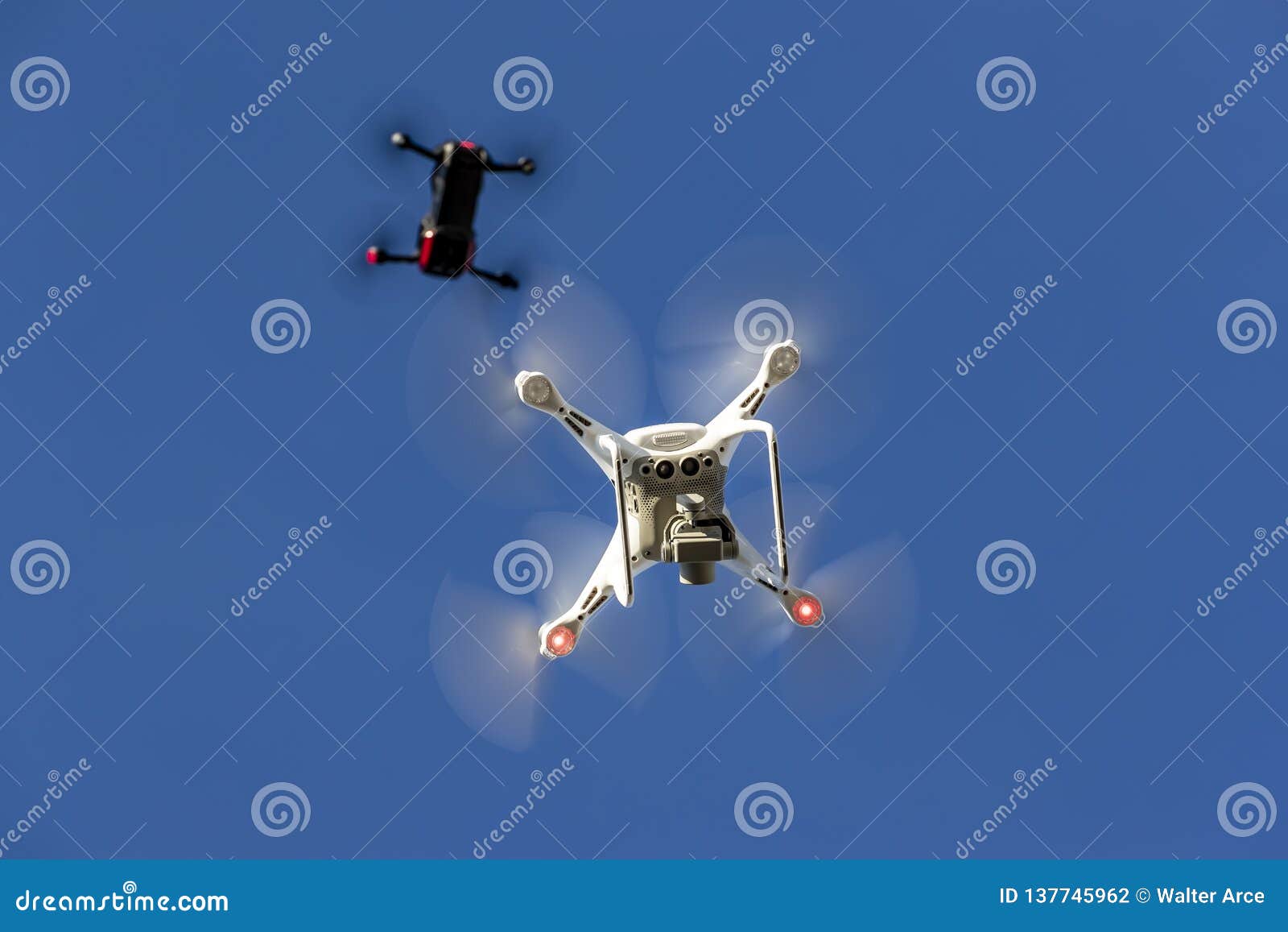 A Group of Drones Fly Together through the Air Against a Blue Sky Stock ...