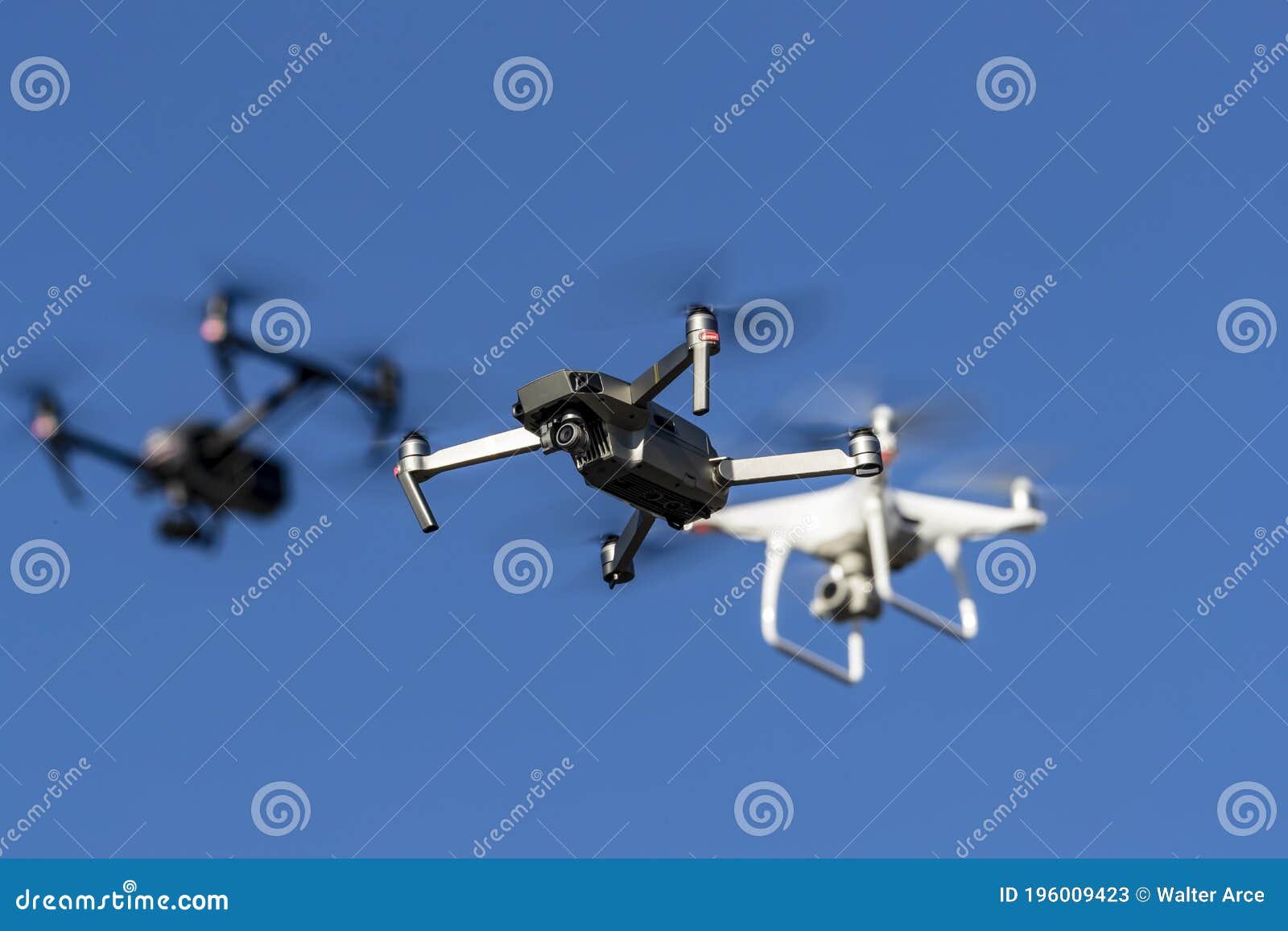 A Group of Drones Fly Together through the Air Against a Blue Sky Stock ...