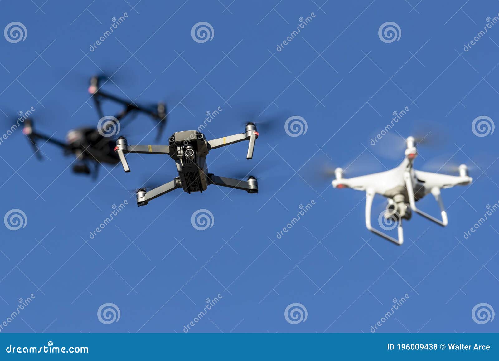 A Group of Drones Fly Together through the Air Against a Blue Sky Stock ...