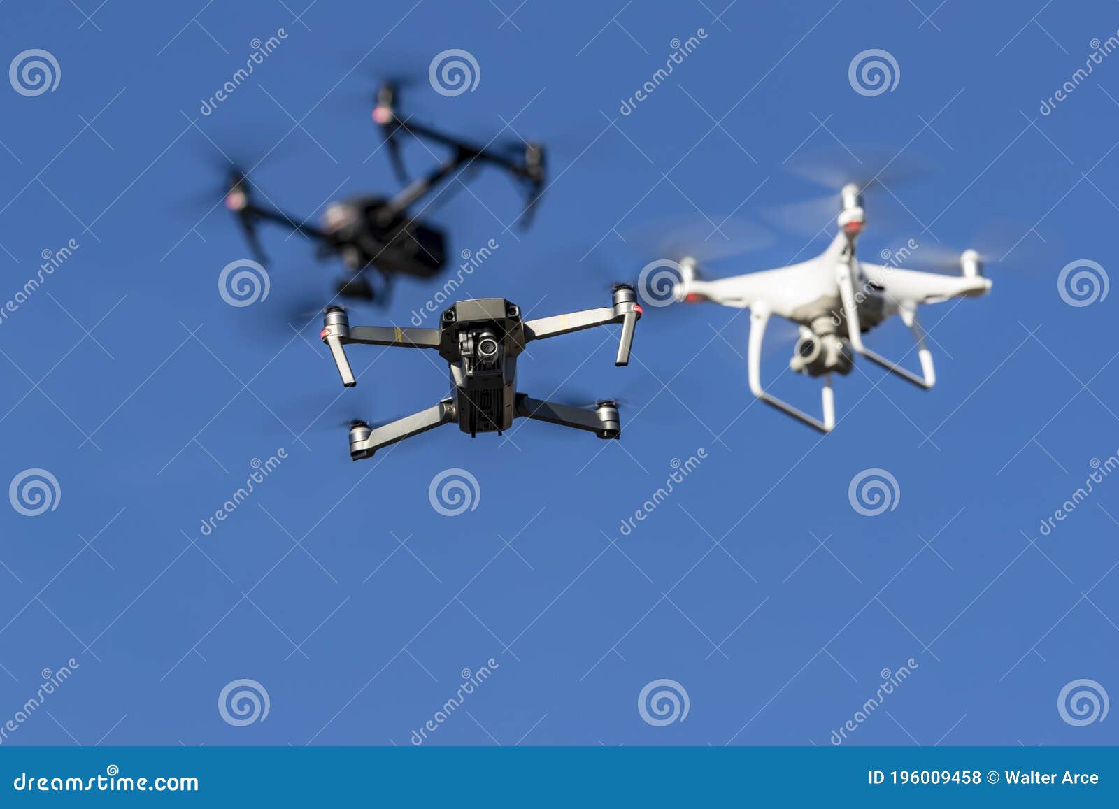 A Group of Drones Fly Together through the Air Against a Blue Sky Stock ...