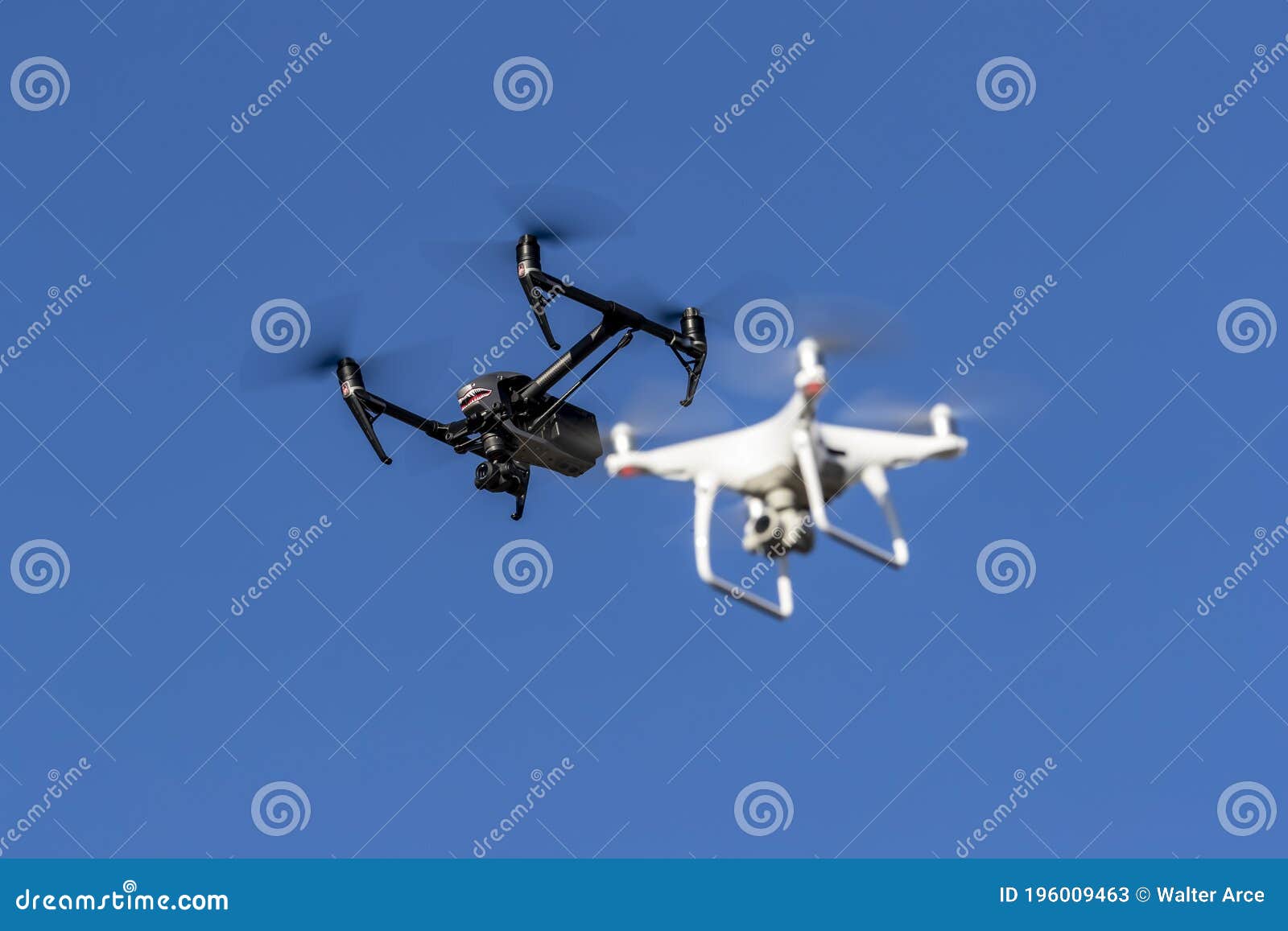 A Group of Drones Fly Together through the Air Against a Blue Sky Stock ...