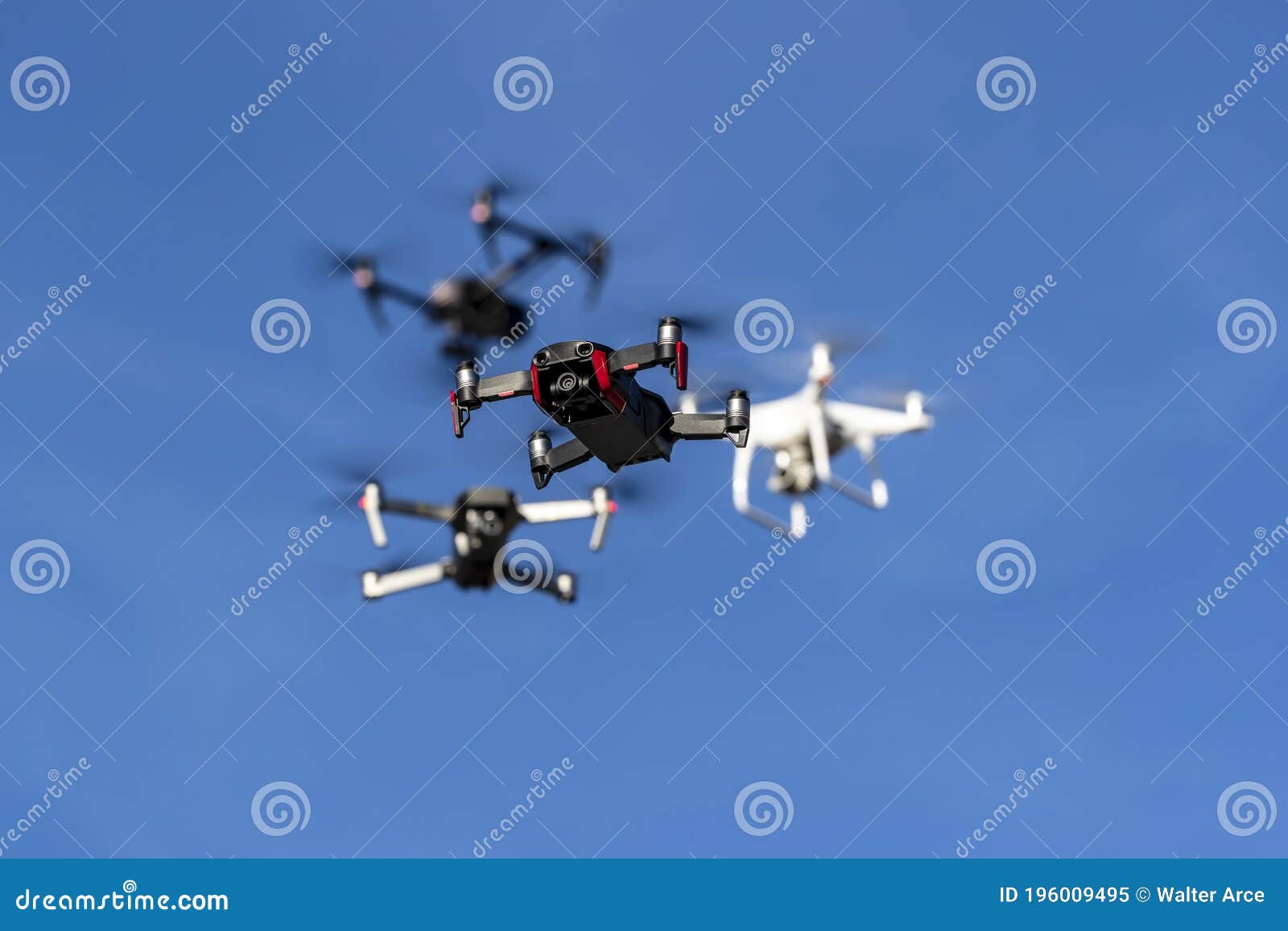 A Group of Drones Fly Together through the Air Against a Blue Sky Stock ...