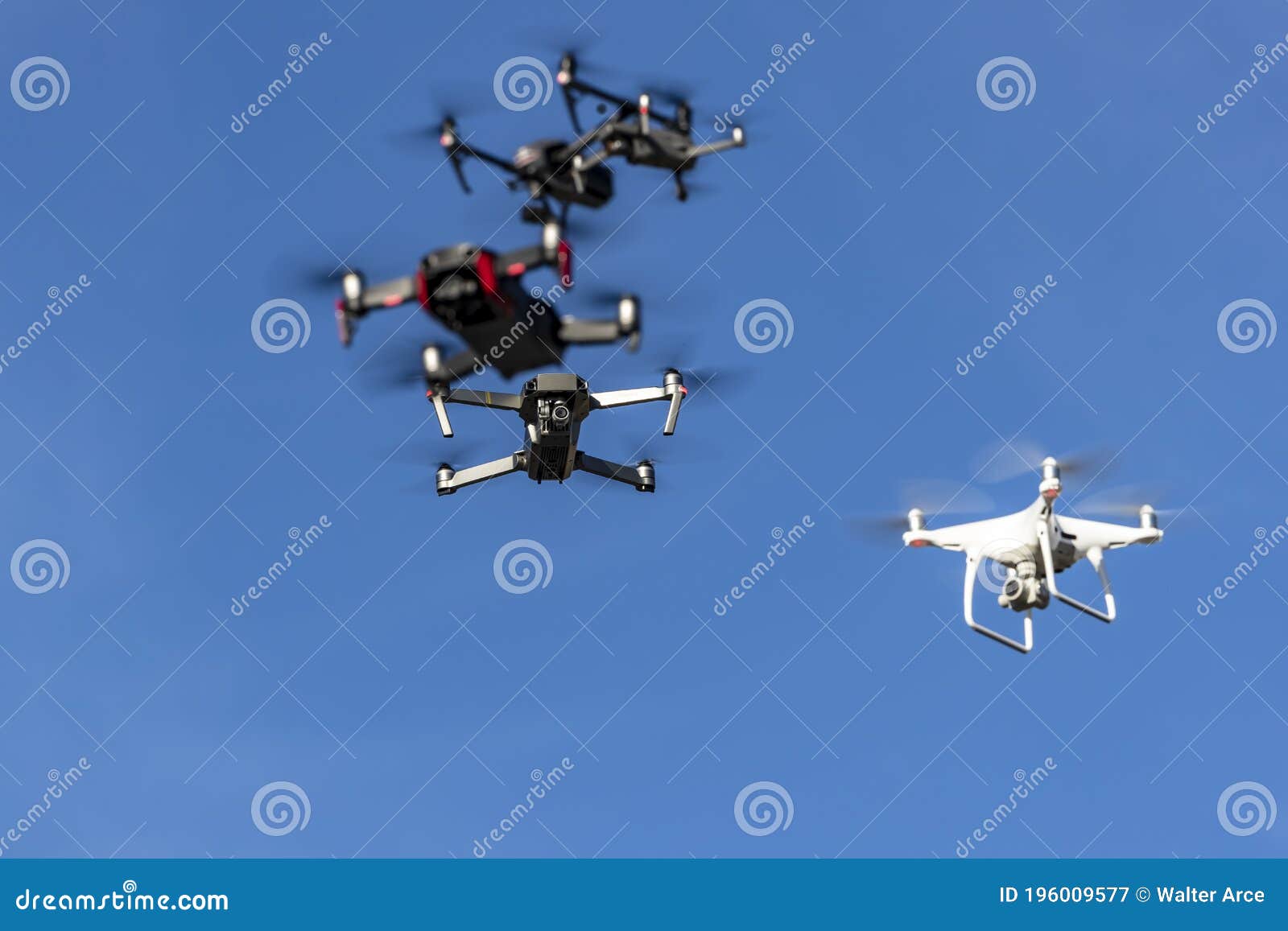 A Group of Drones Fly Together through the Air Against a Blue Sky Stock ...