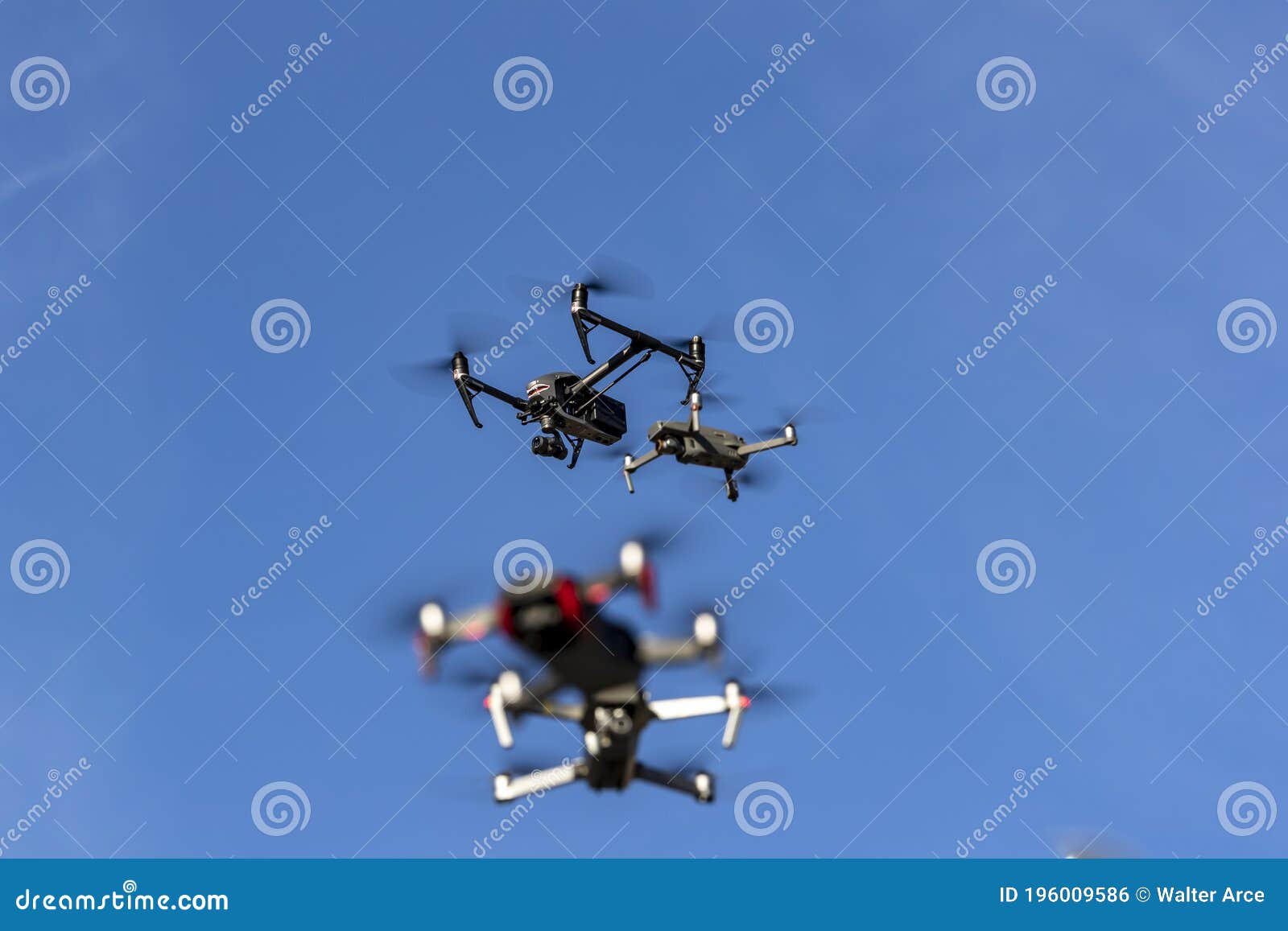 A Group of Drones Fly Together through the Air Against a Blue Sky Stock ...