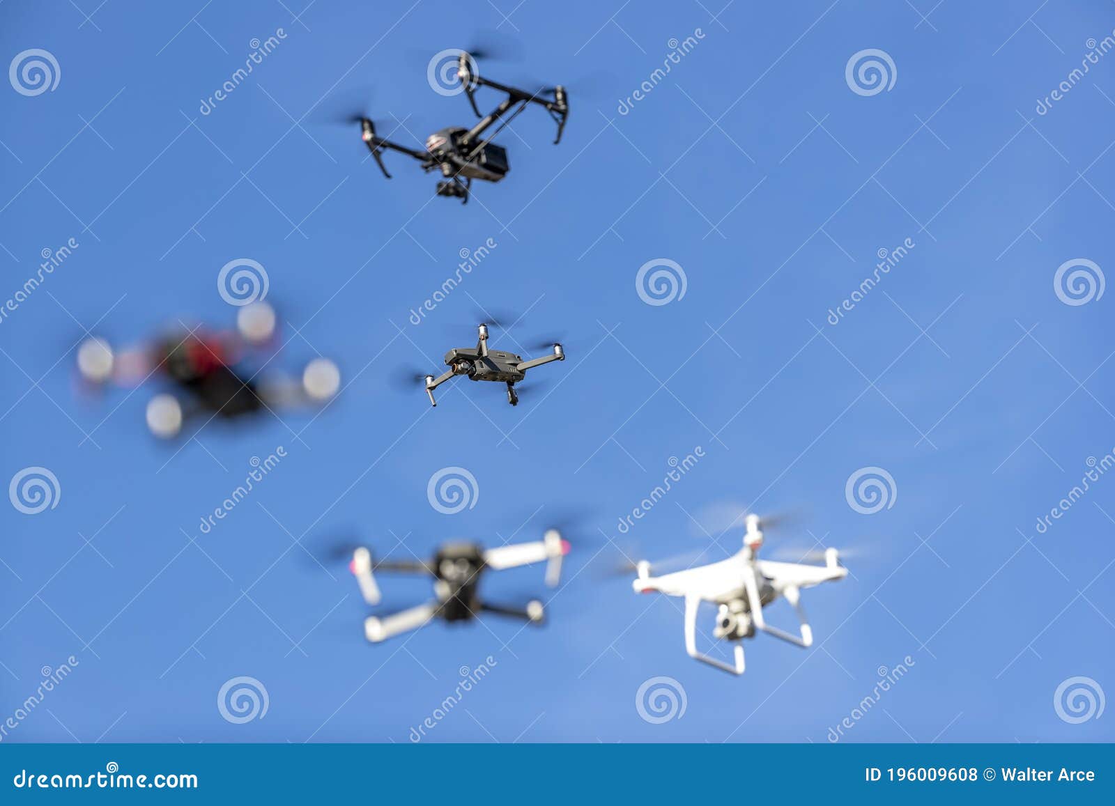 A Group of Drones Fly Together through the Air Against a Blue Sky Stock ...