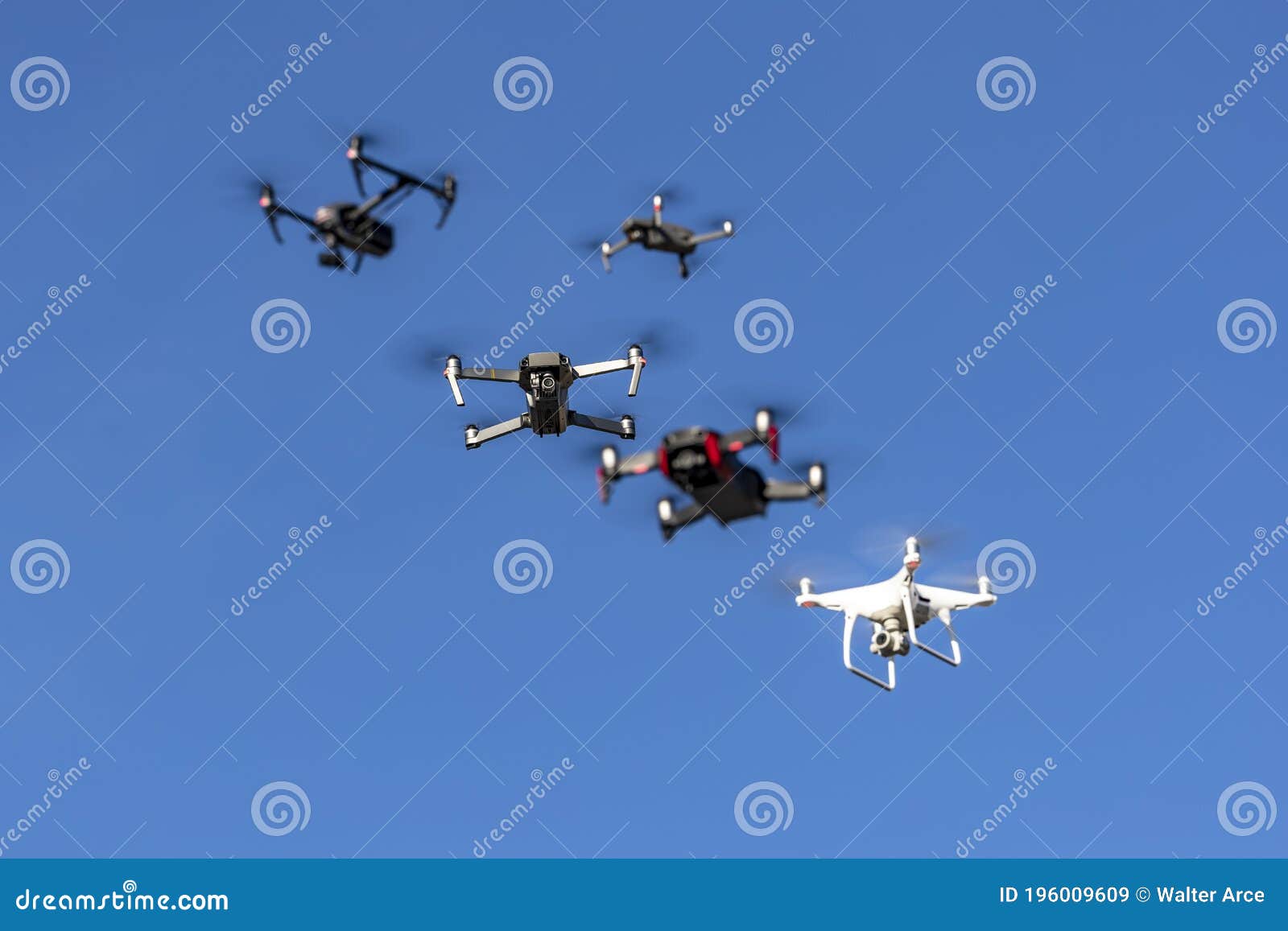 A Group of Drones Fly Together through the Air Against a Blue Sky Stock ...