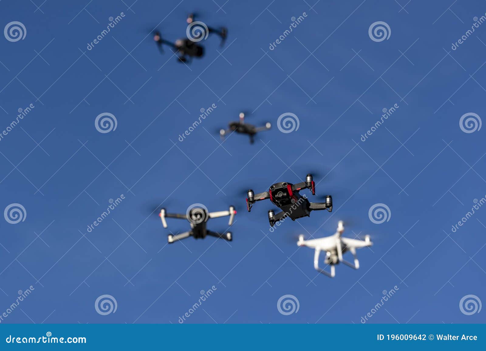A Group of Drones Fly Together through the Air Against a Blue Sky Stock ...