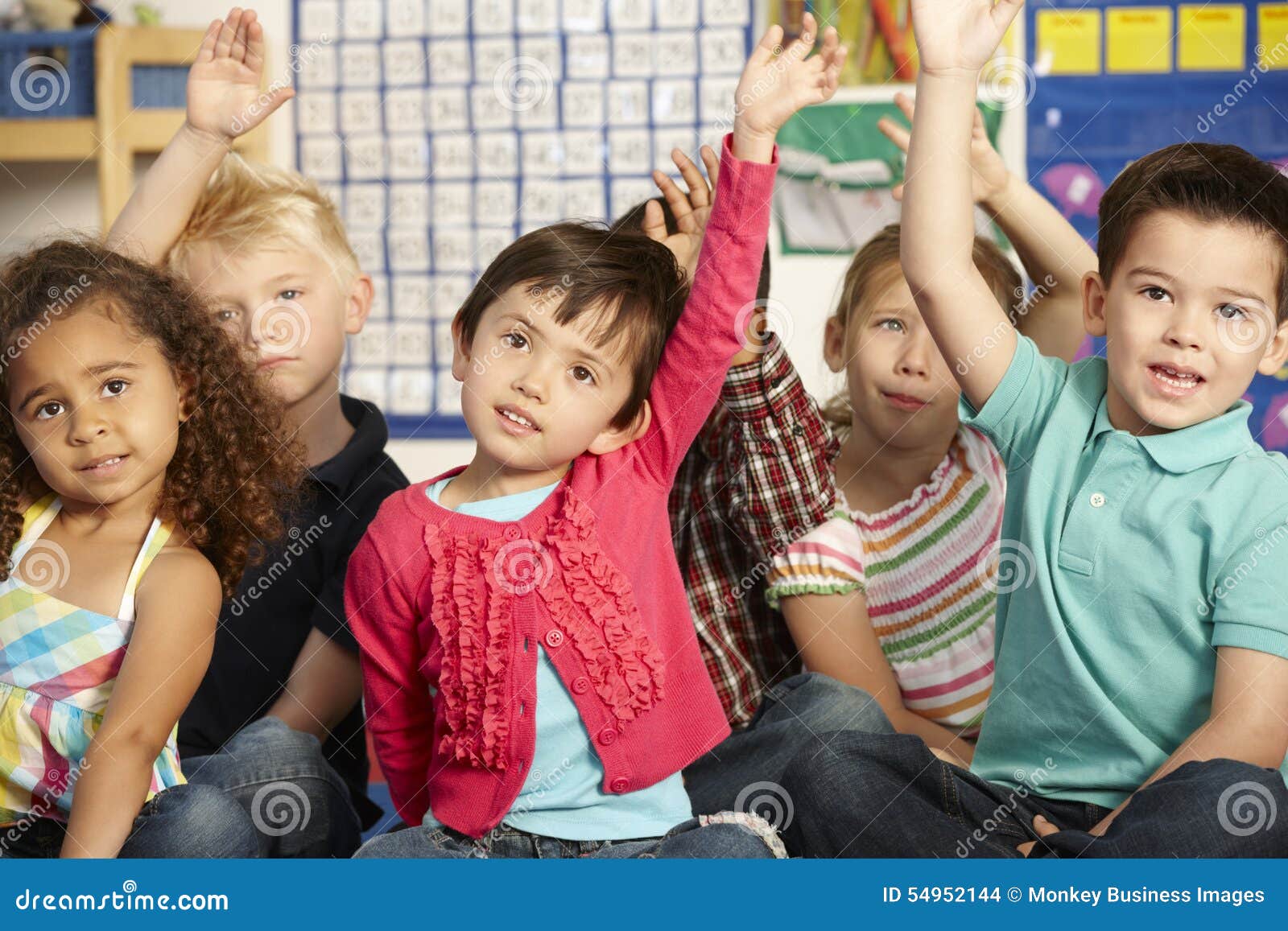 Group of Elementary Age Schoolchildren Answering Question in Class ...