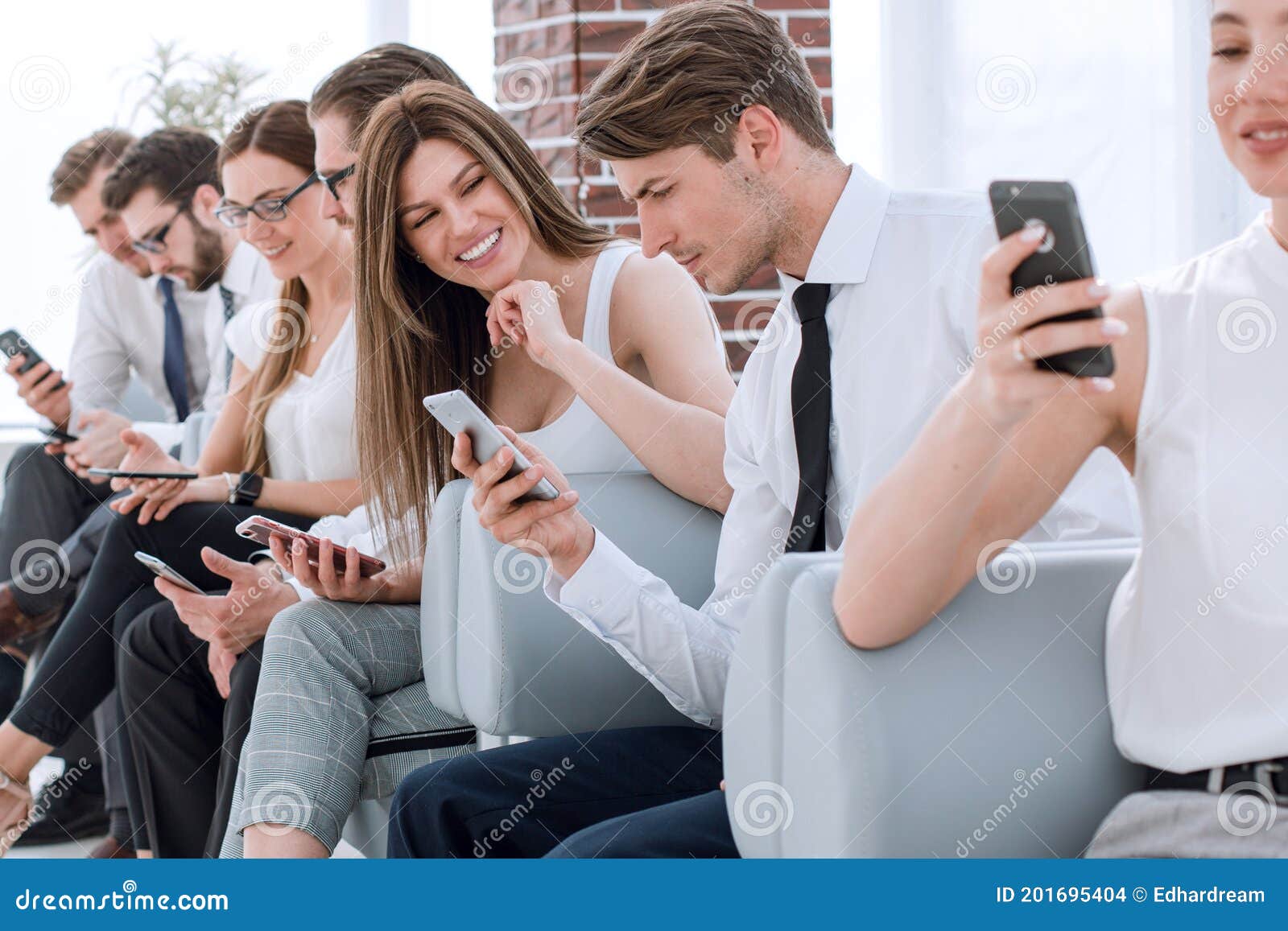 Group of Employees Using Their Gadgets Sitting in the Office Hallway ...