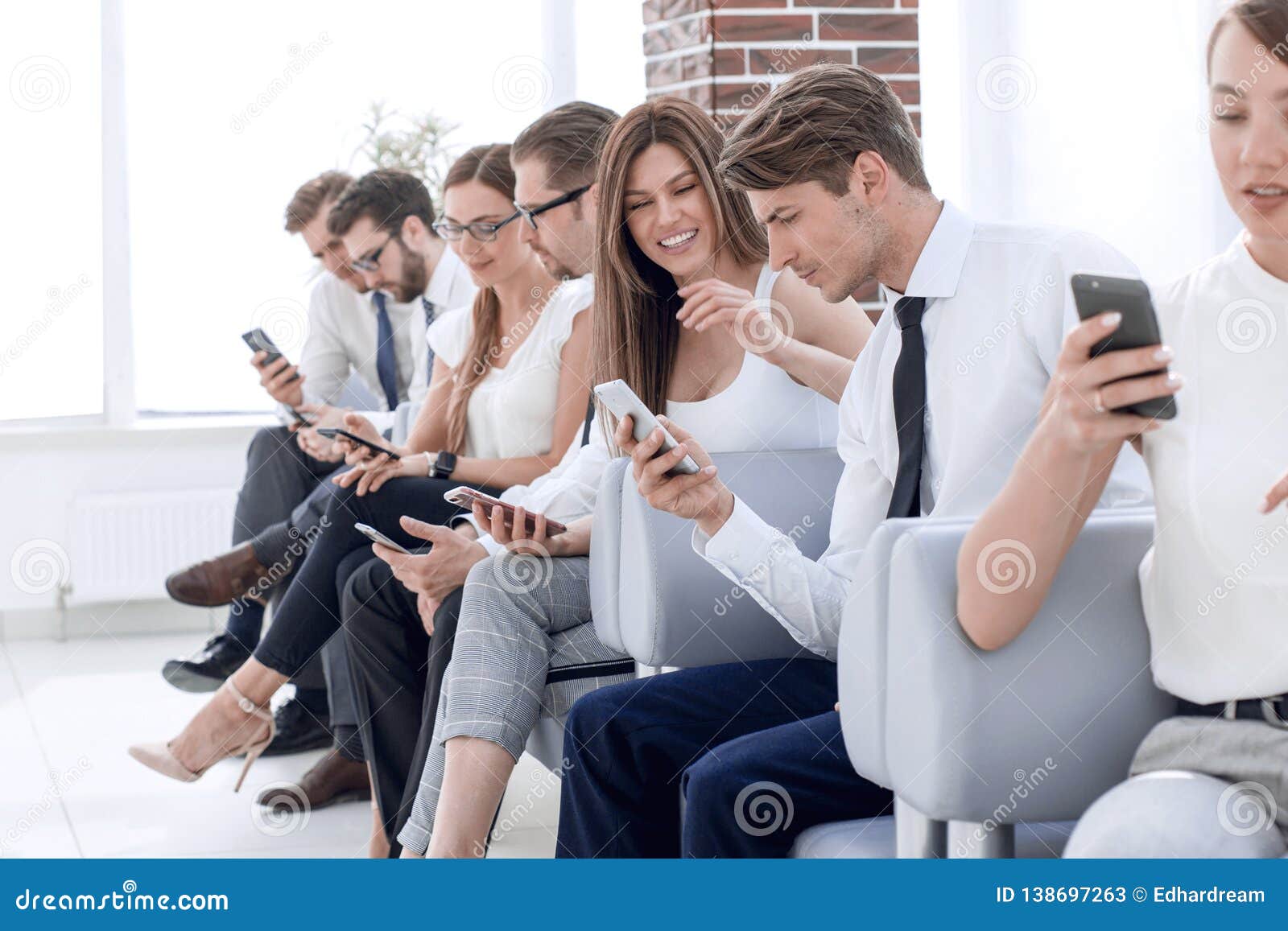 Group of Employees Using Their Gadgets Sitting in the Office Hallway ...