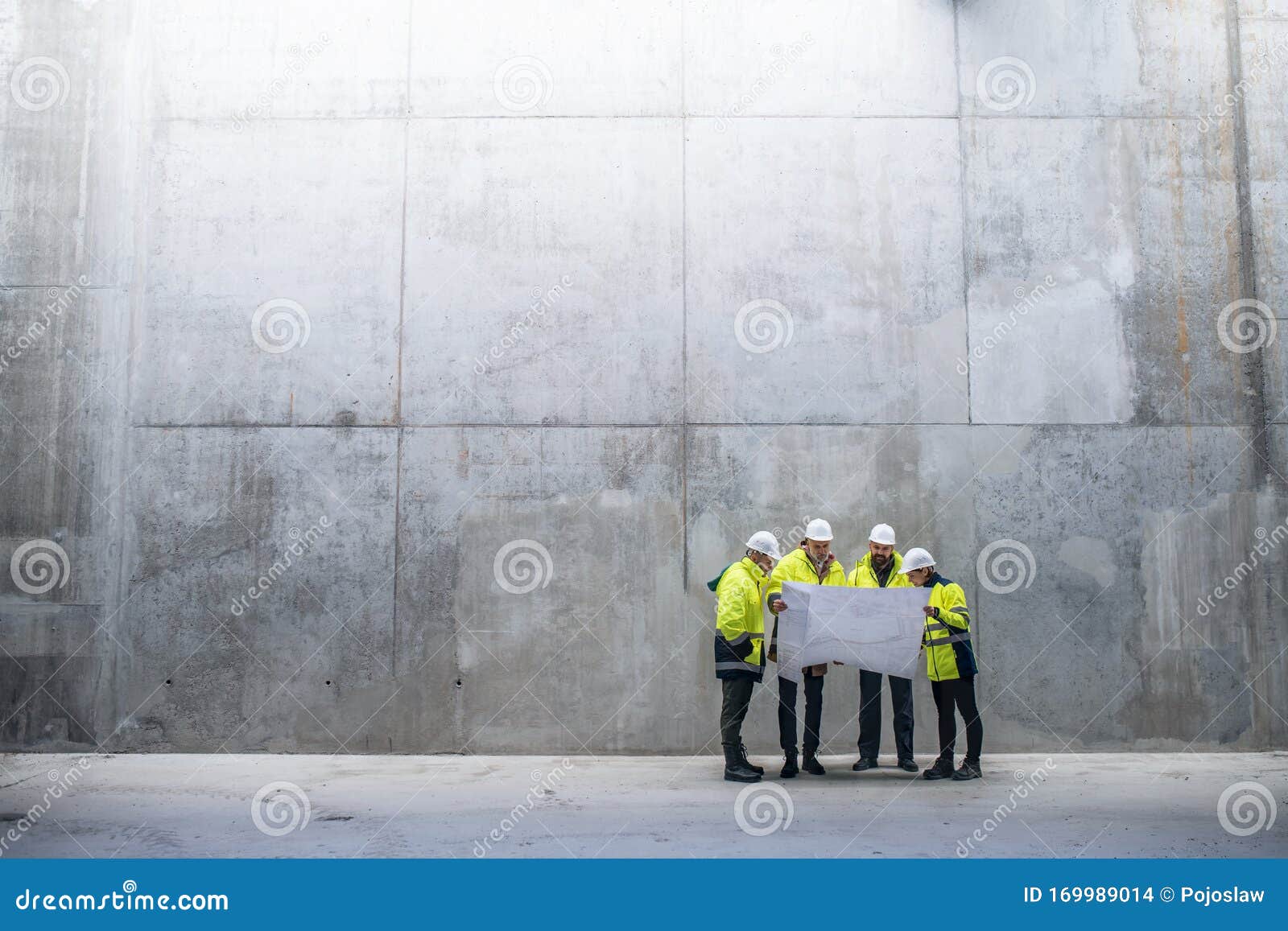 A Group of Engineers Standing Against Concrete Wall on Construction ...