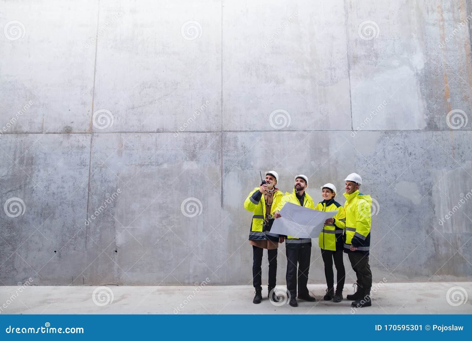 A Group of Engineers Standing Against Concrete Wall on Construction ...