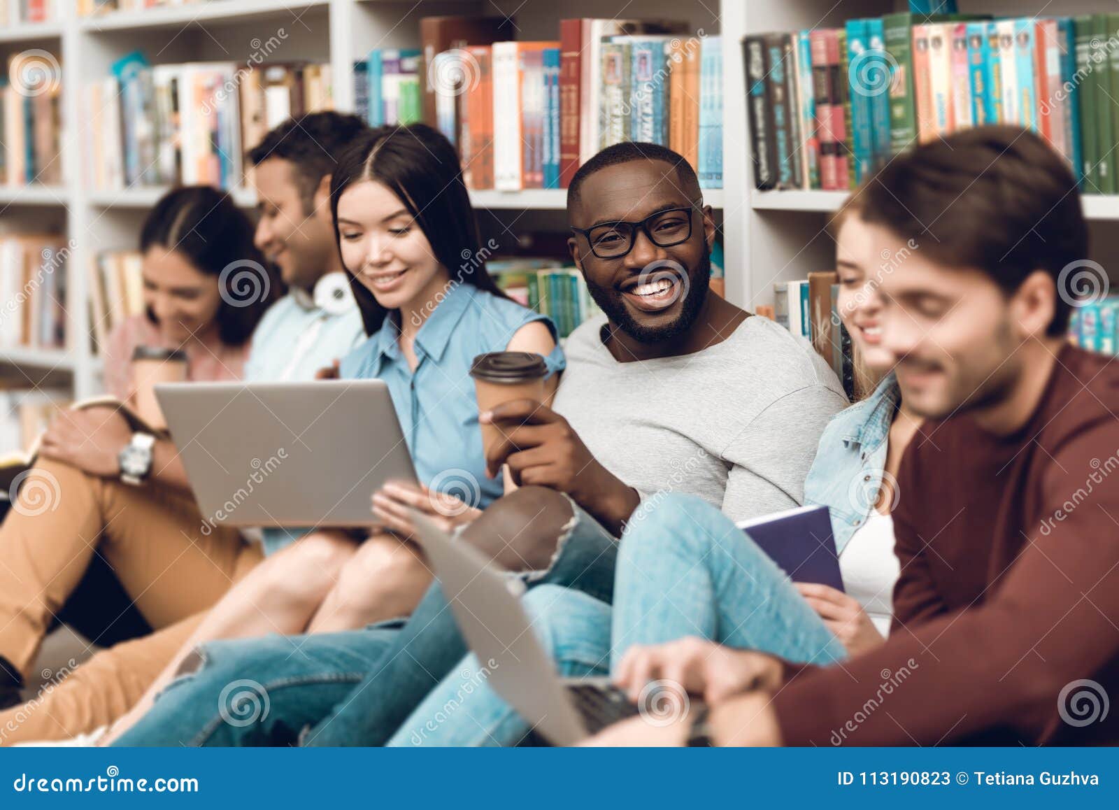 Group of Ethnic Multicultural Students Sitting Near Bookshelf in ...