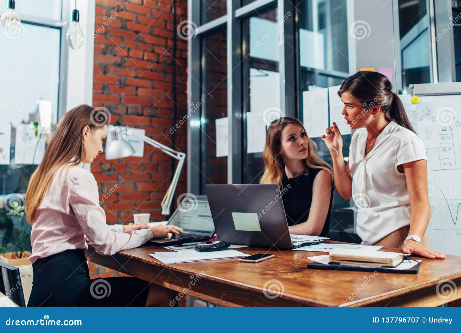 Group of Female Executives Sitting with Laptops and Documents at Desk ...