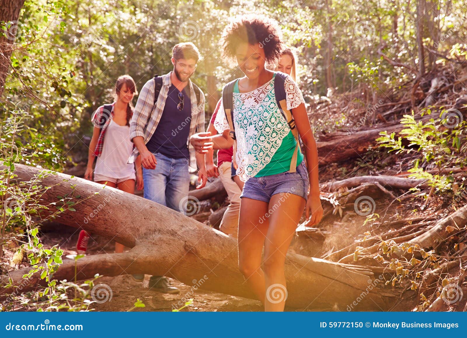Group of Friends Jumping Over Tree Trunk on Countryside Walk Stock ...