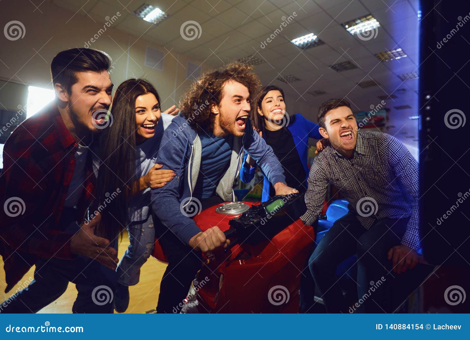 A Group of Friends Playing Arcade Machine. Stock Photo - Image of happy ...