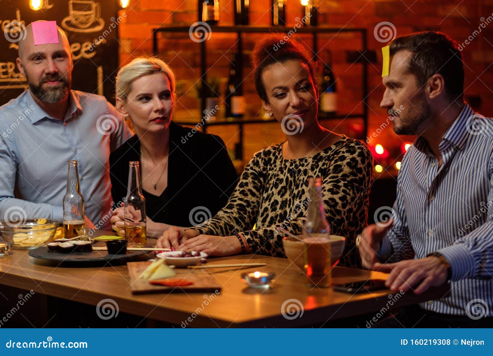Group of Friends Playing Sticky Head Game Behind Bar Counter in a Cafe ...