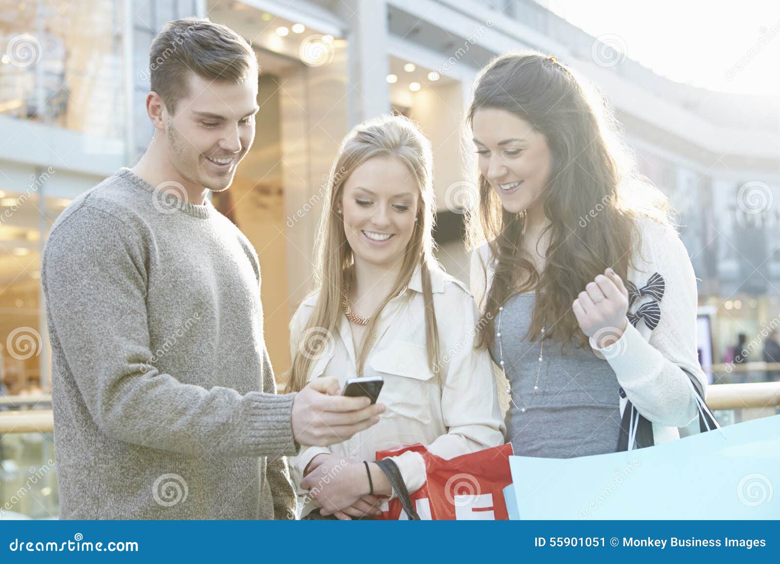 Group of Friends Shopping in Mall Looking at Mobile Phone Stock Image ...