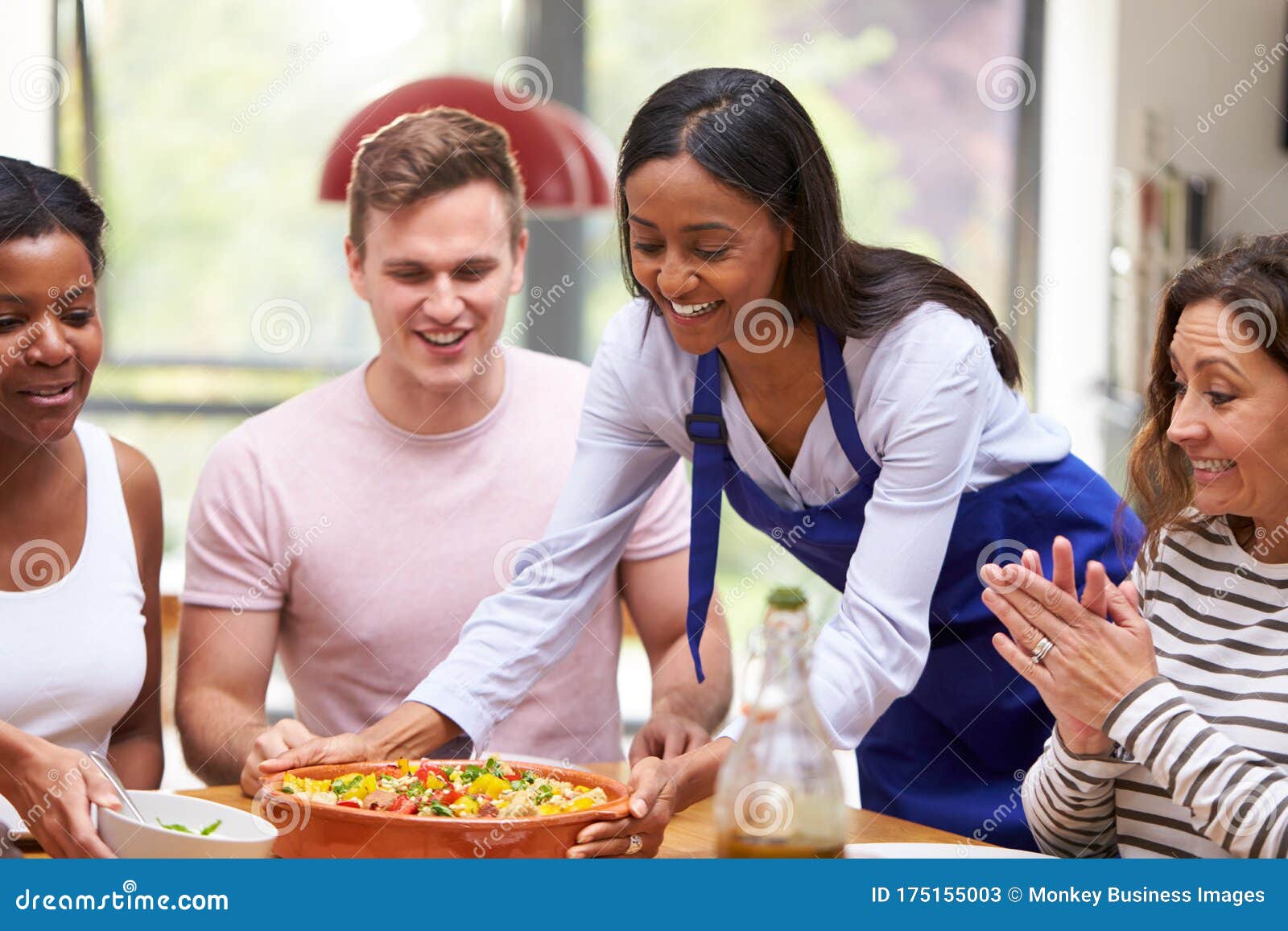 Group of Friends Sitting Around Table Eating Meal at Home Together ...