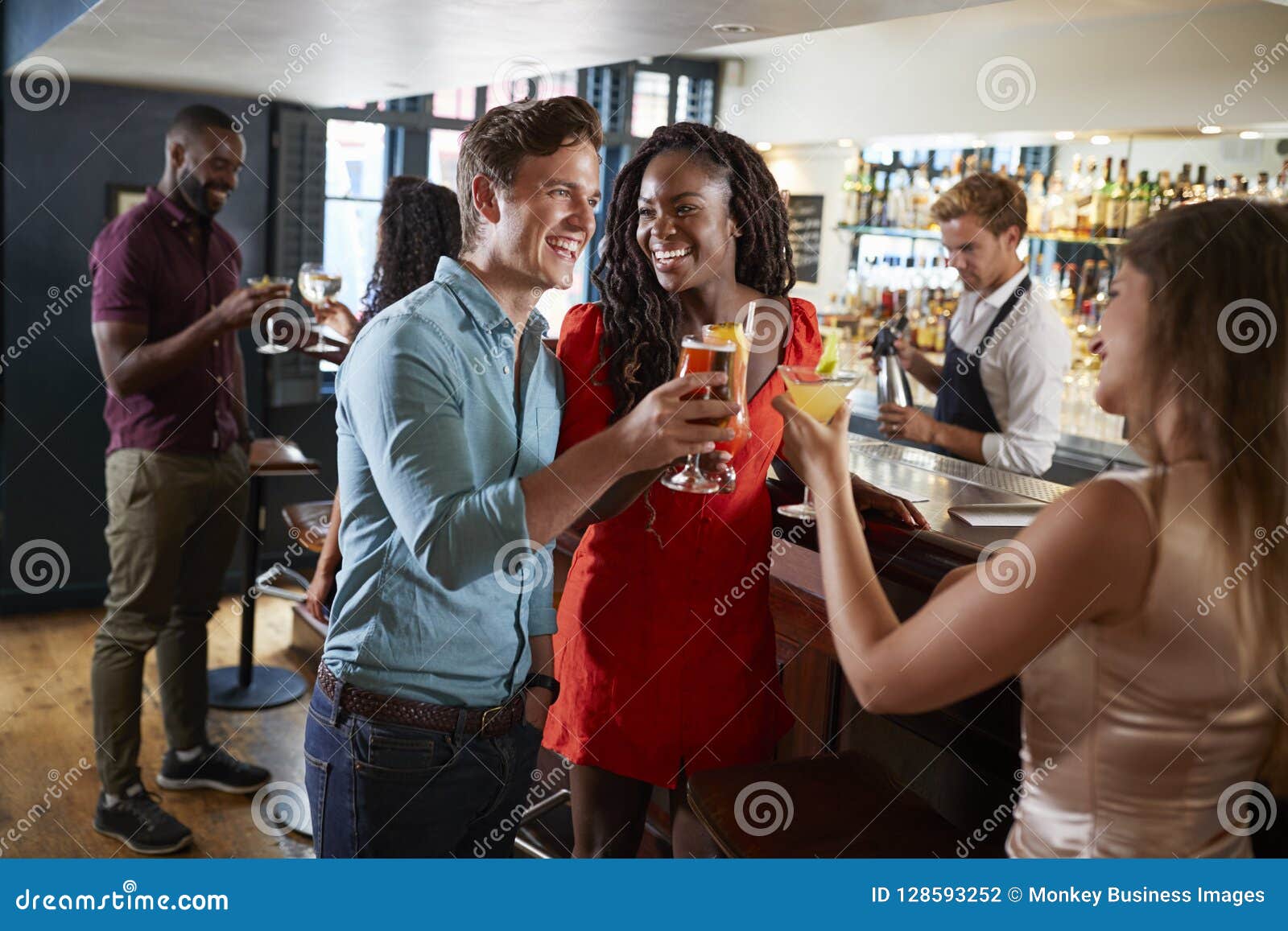 Group of Friends Standing at Bar and Making a Toast on Night Out Stock ...