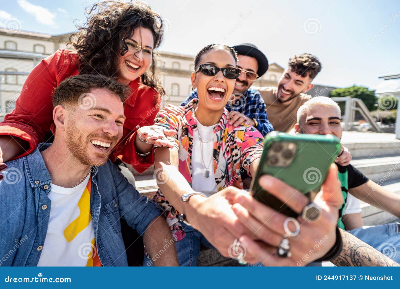 Group Of Happy Multiracial Friends Using Smartphone Outdoors Watching