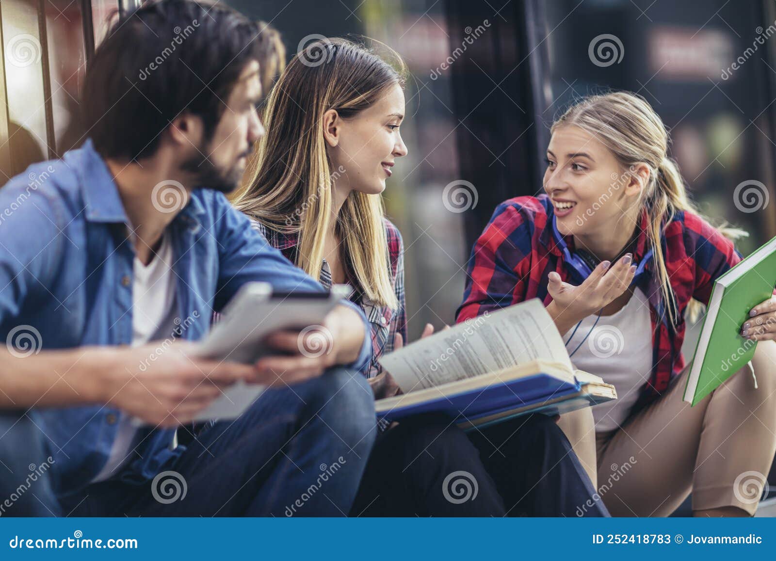 Happy University Students Talking while Sitting Outdoors at Campus ...