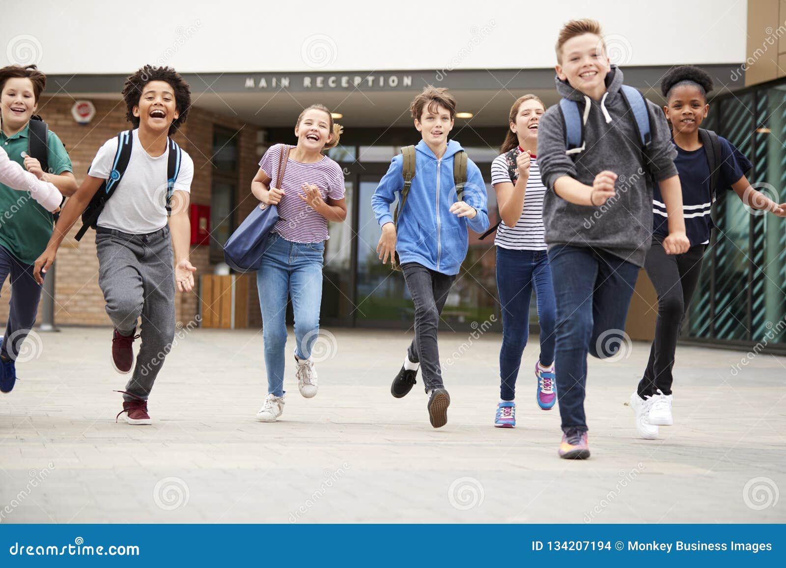 Group of High School Students Running Out of School Buildings Towards ...