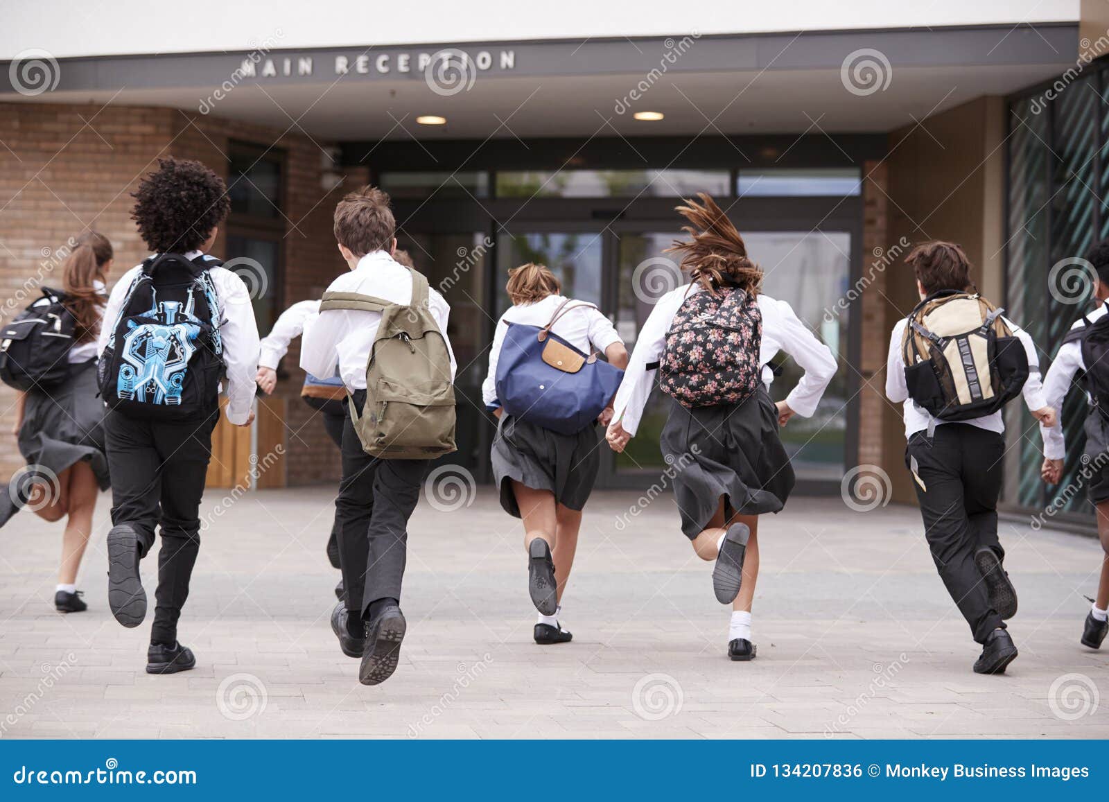Group of High School Students Wearing Uniform Running into School ...