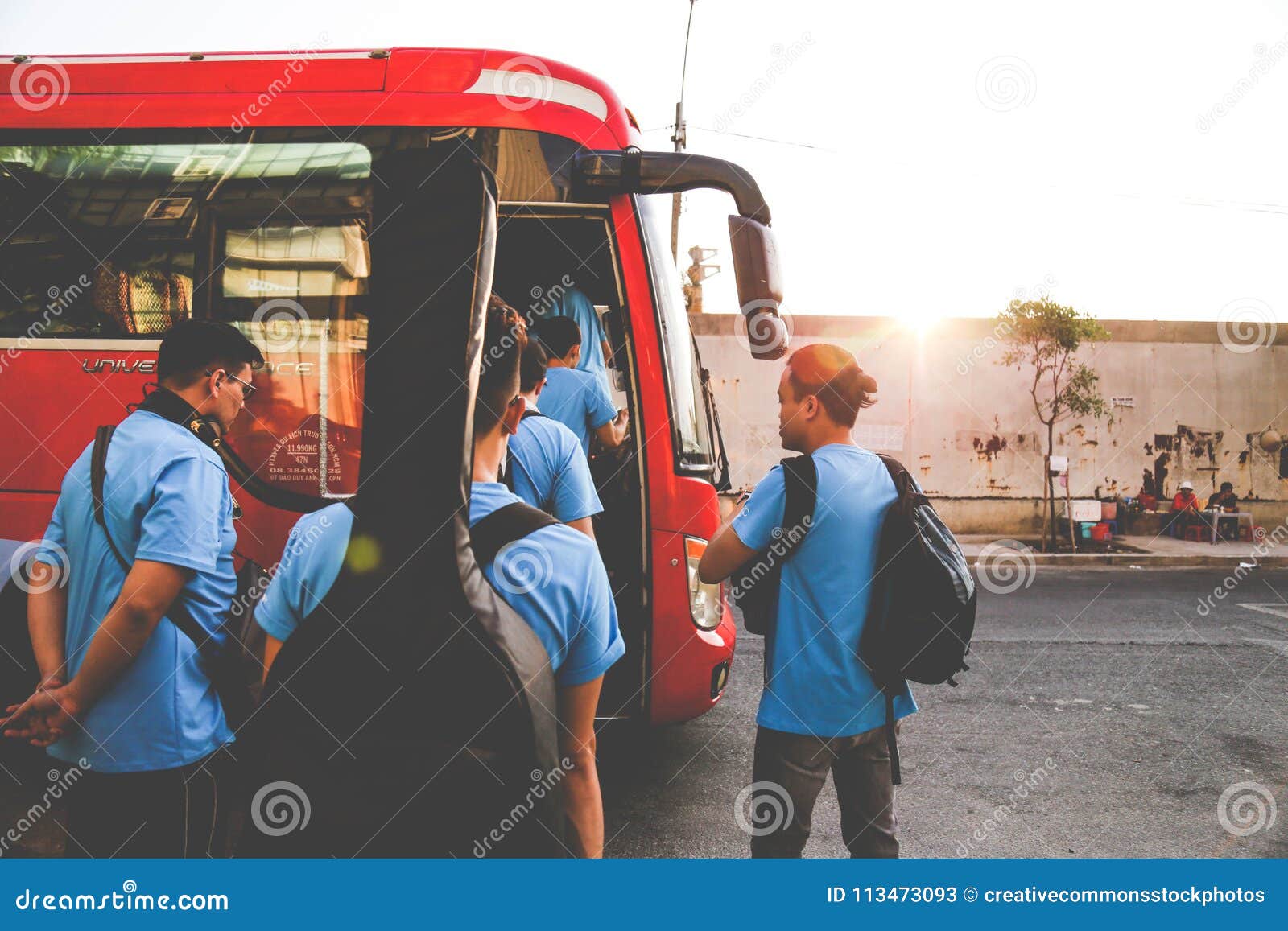 Group Of Men Wearing Blue Shirts About To Enter Red Bus Picture. Image ...