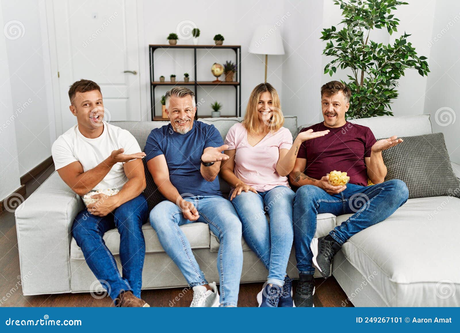 Group of Middle Age People Sitting on the Sofa at Home Pointing Aside ...